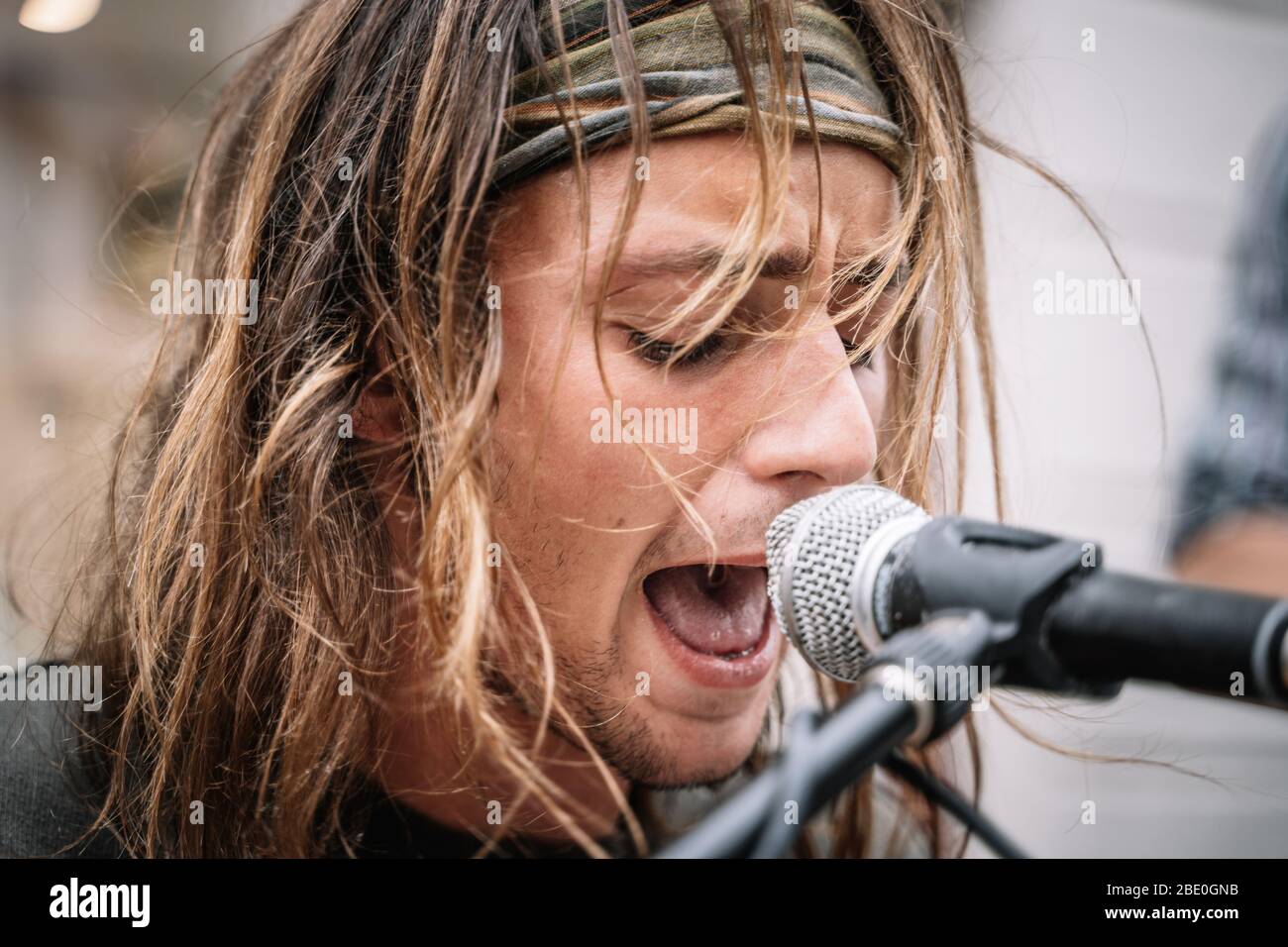 Detail of the face of a young rocker looking man singing with emotion ...