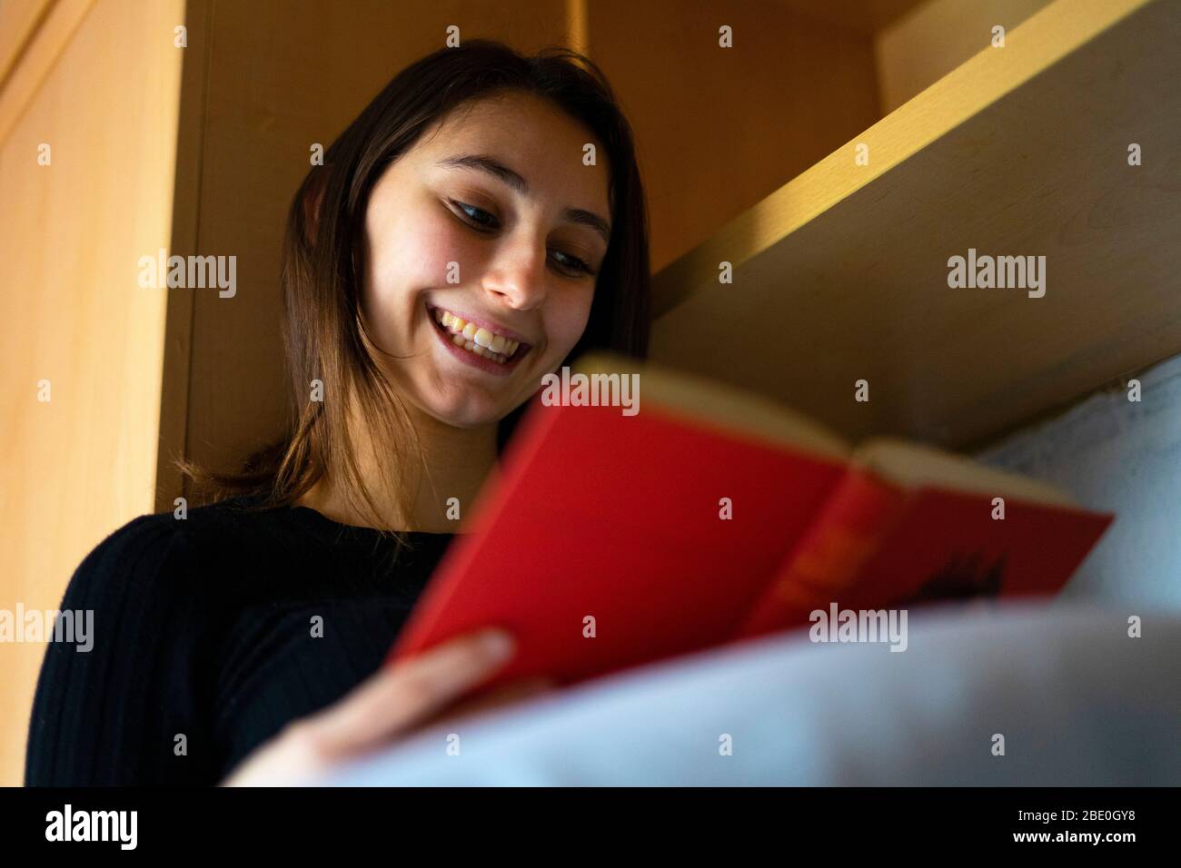 Young woman lying in bed and reading a book hi-res stock photography ...
