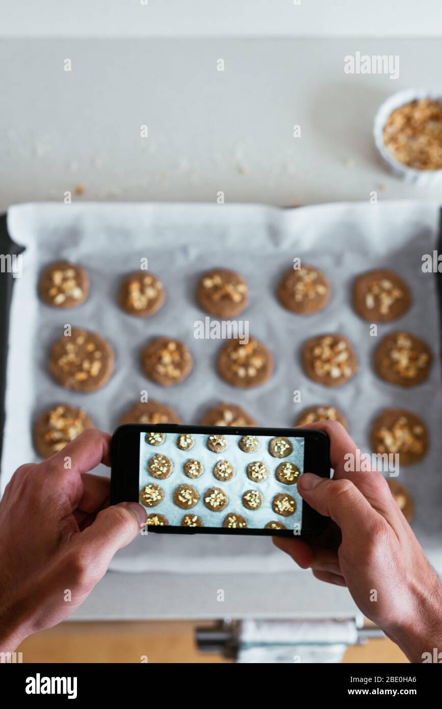 Overhead view of a young man taking a photo of his home-made cookies ...
