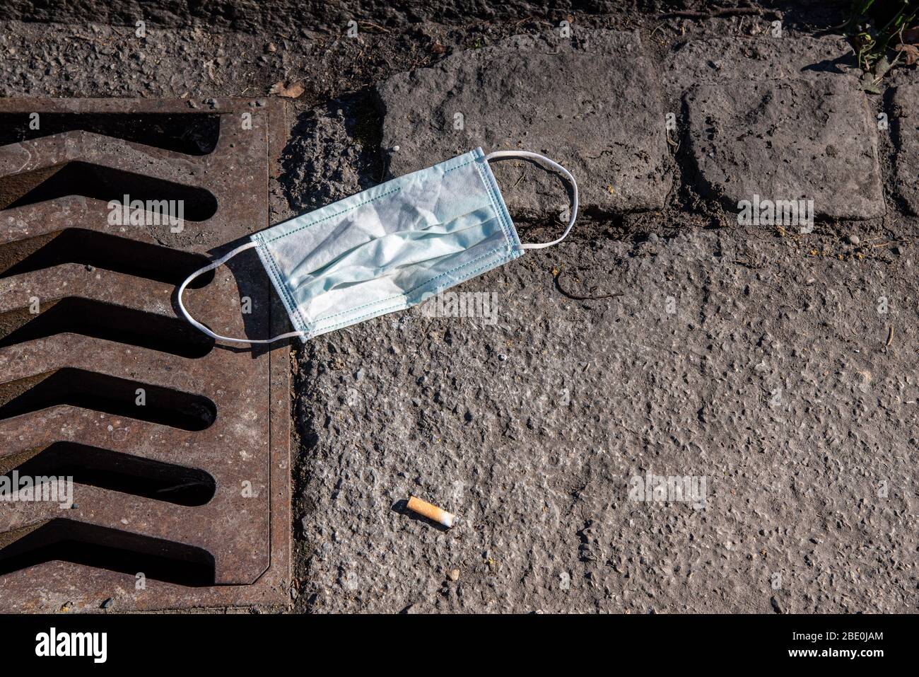 Discarded face mask lies on the floor next to the sewer manhole Stock ...