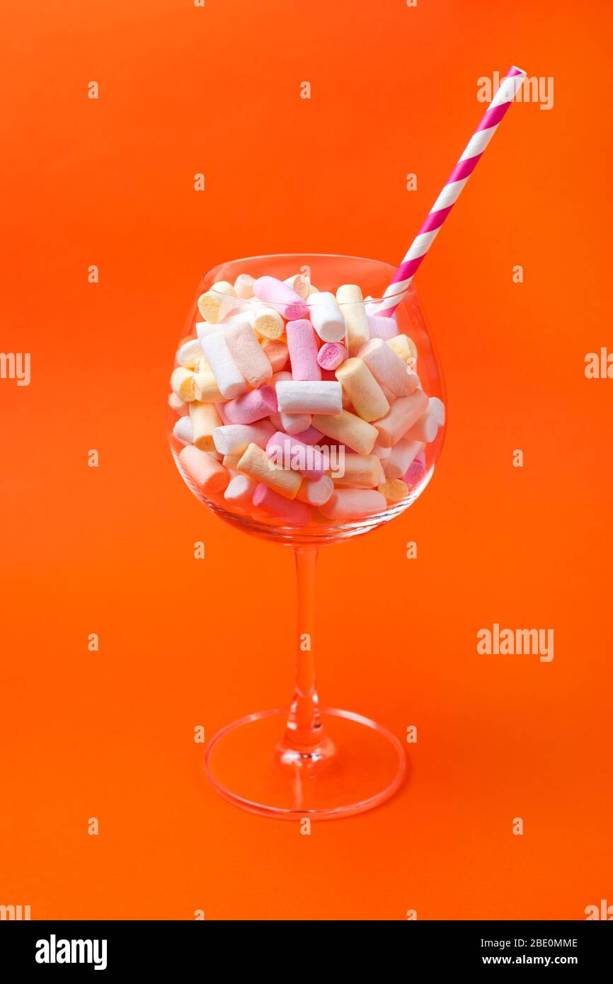 Mini marshmallows in a glass on a bright orange background. Multi ...