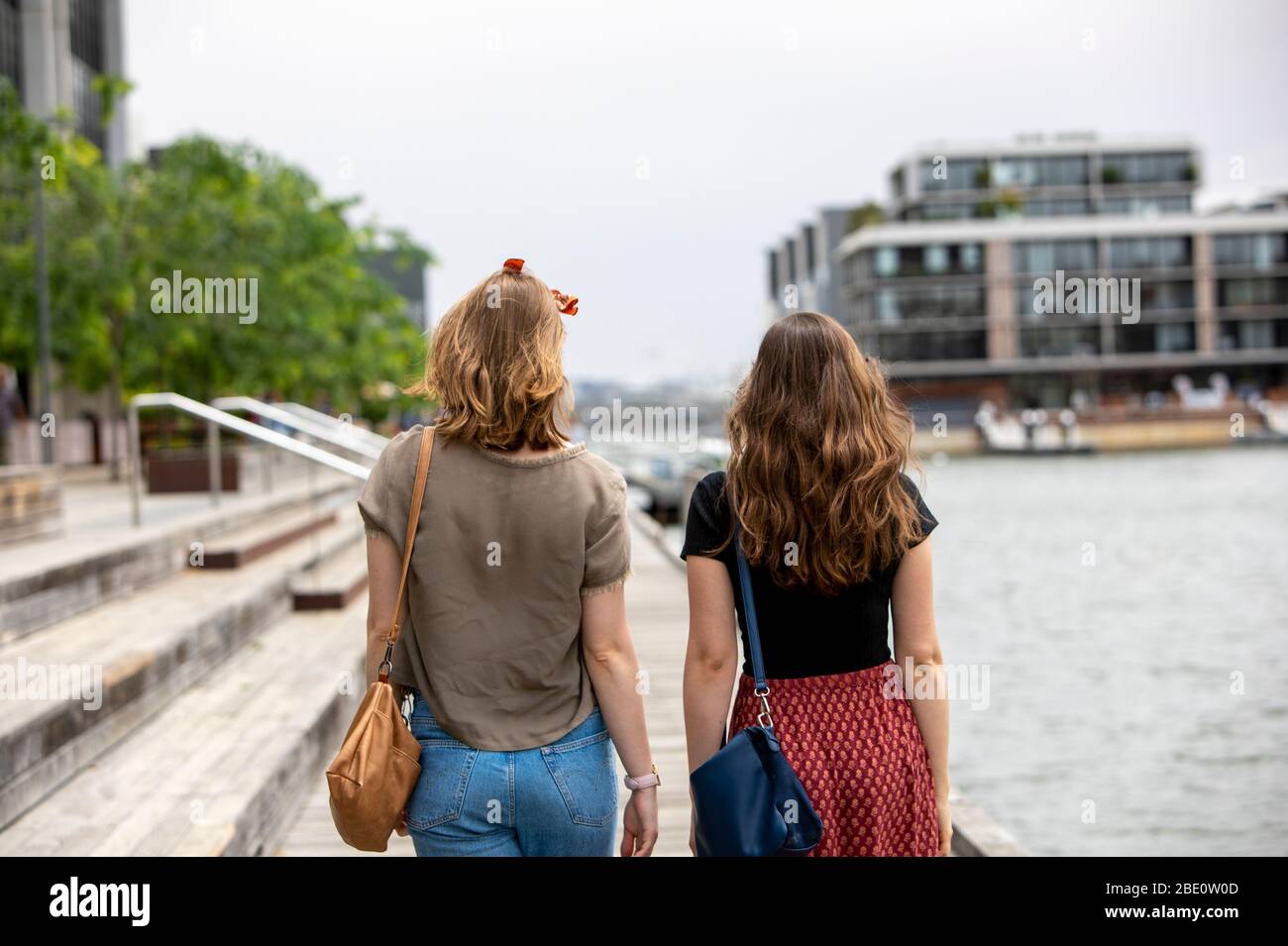 Back view of two women walking along a marina Stock Photo - Alamy