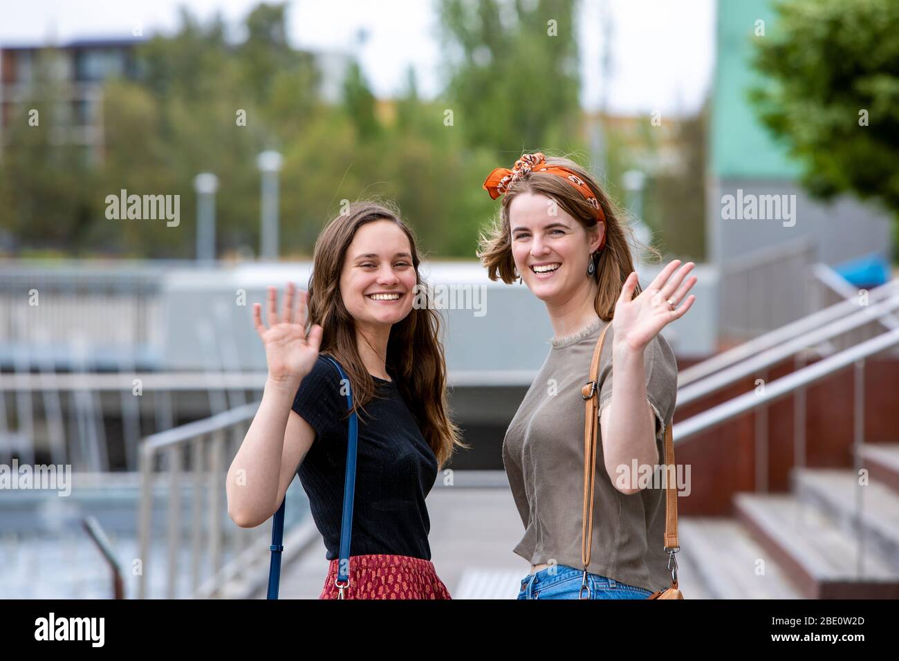 Two girls turning to the camera and waving Stock Photo - Alamy