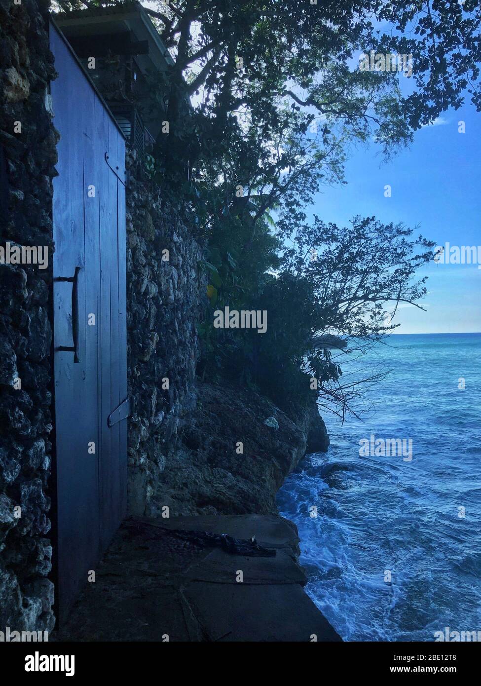 Large door near the beach, next to the waves of the sea, with trees and ...