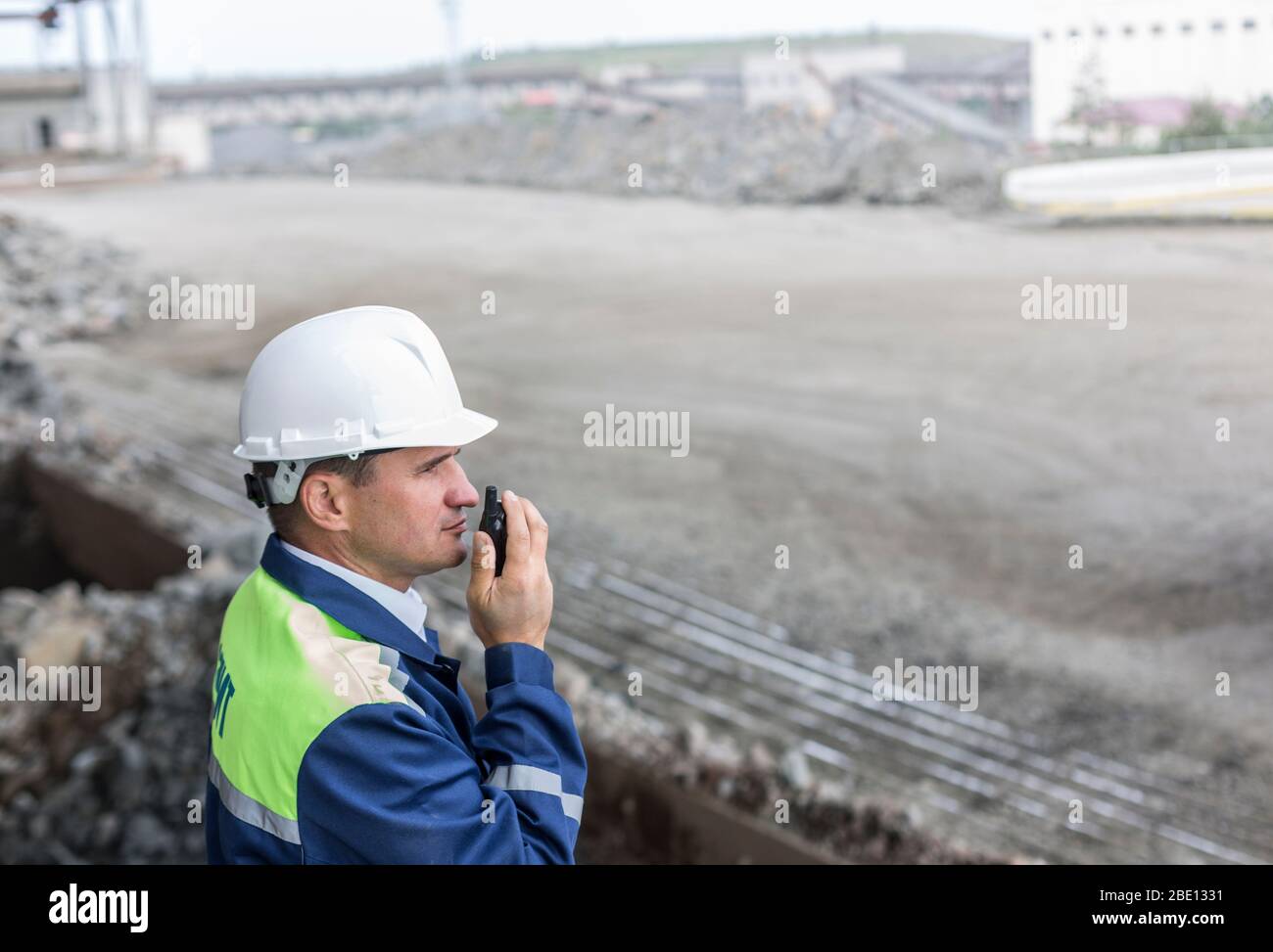 Mining engineer in yellow-blue uniform white helmet supervises ...