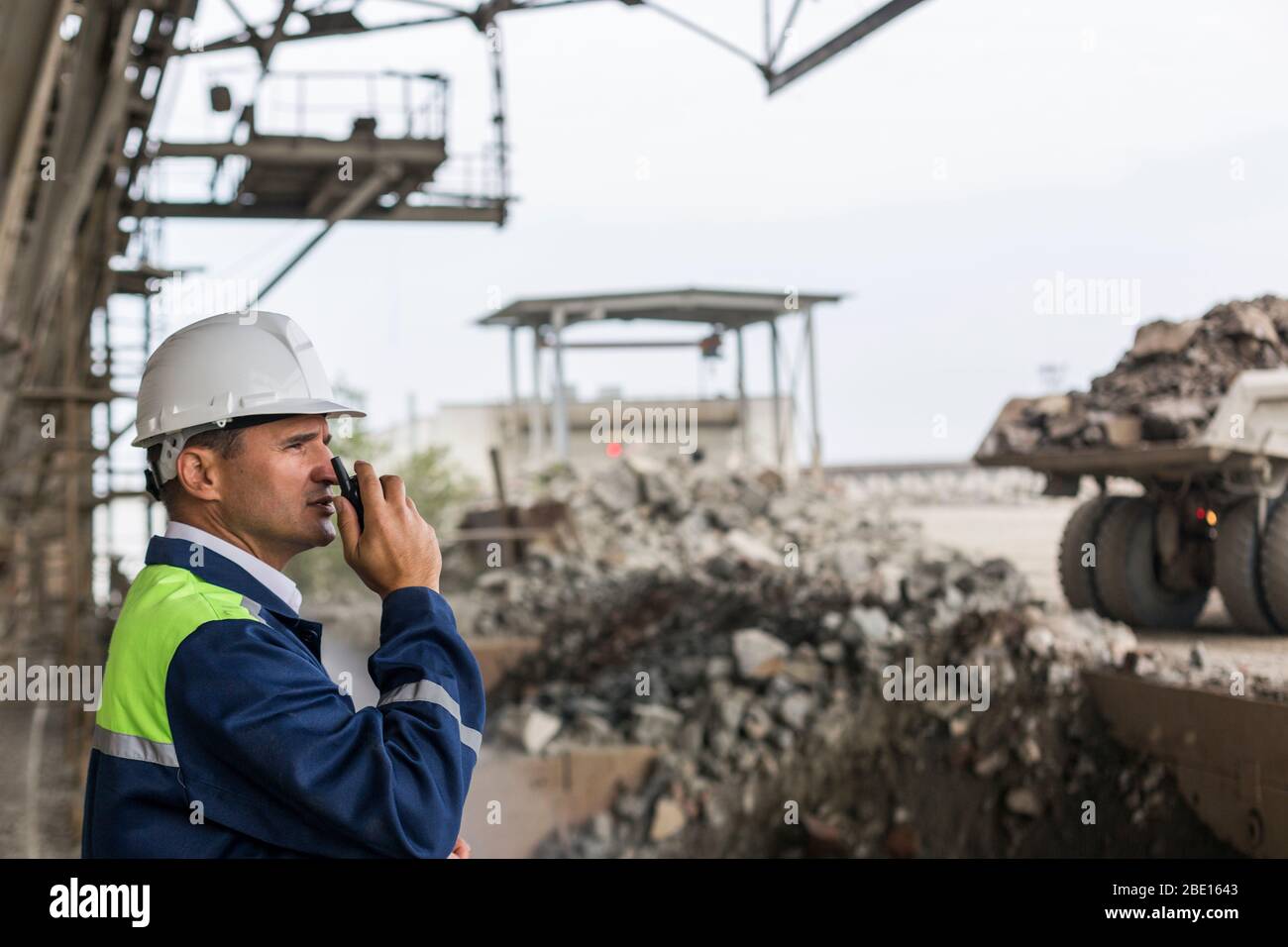Mining engineer in yellow-blue uniform white helmet supervises ...