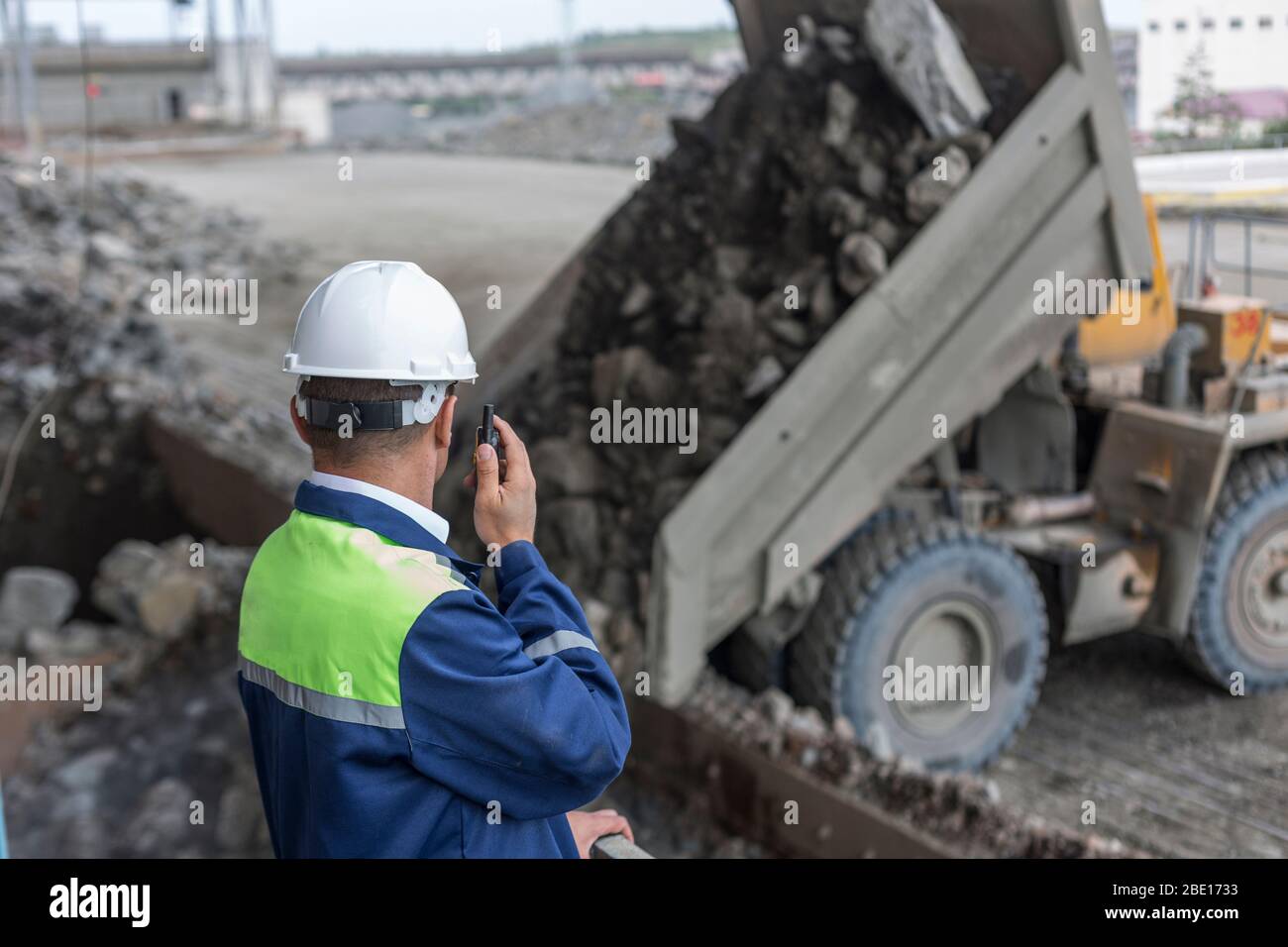 Mining engineer in yellow-blue uniform white helmet supervises ...