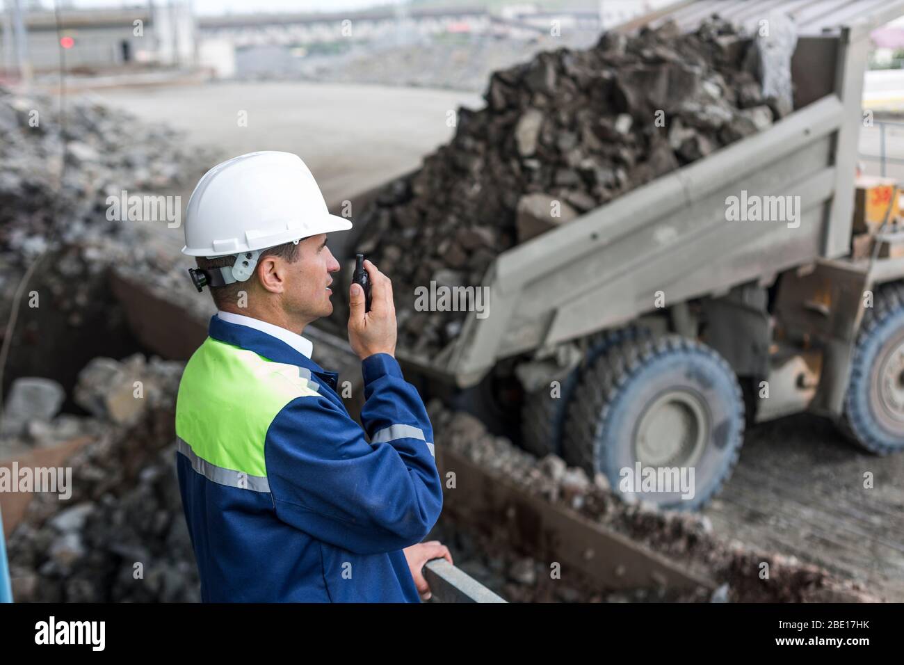 Mining engineer in yellow-blue uniform white helmet supervises ...