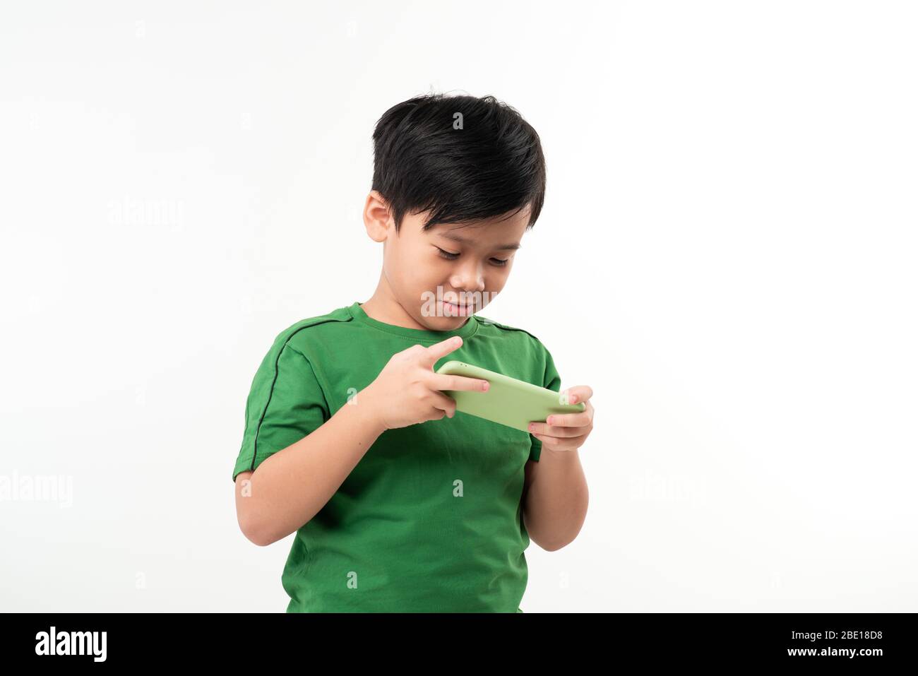 Portrait of an amused cute little kid playing games on smartphone ...