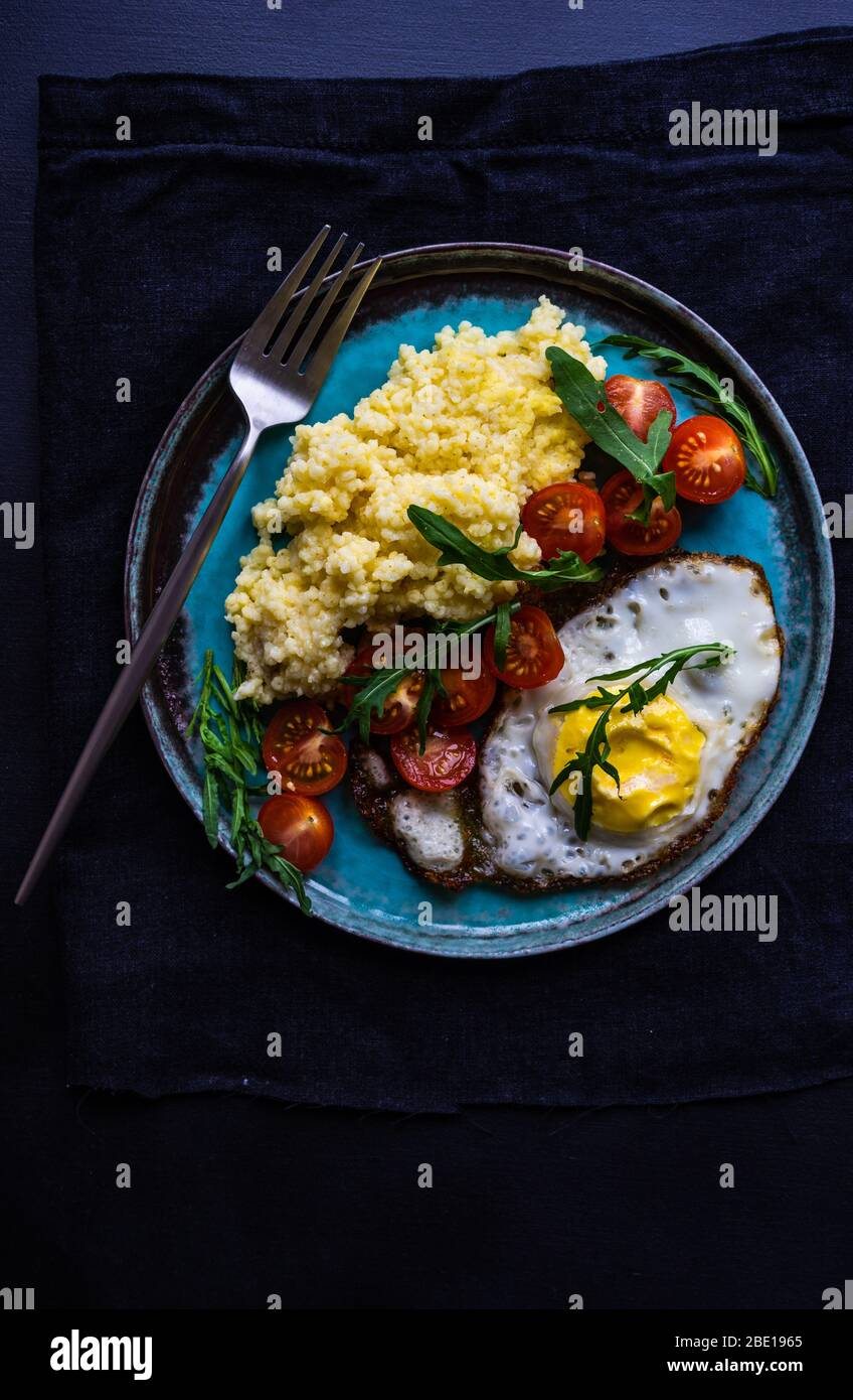 Healthy breakfast concept with millet, fried egg and cherry tomato with ...