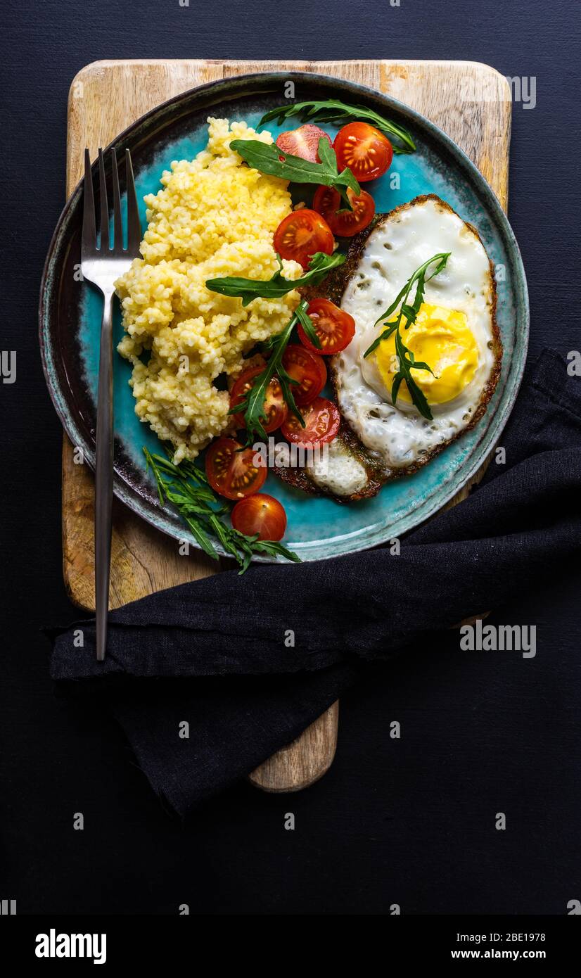 Healthy breakfast concept with millet, fried egg and cherry tomato with ...