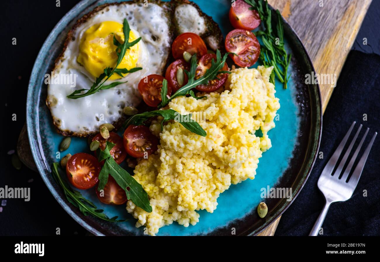 Healthy breakfast concept with millet, fried egg and cherry tomato with ...