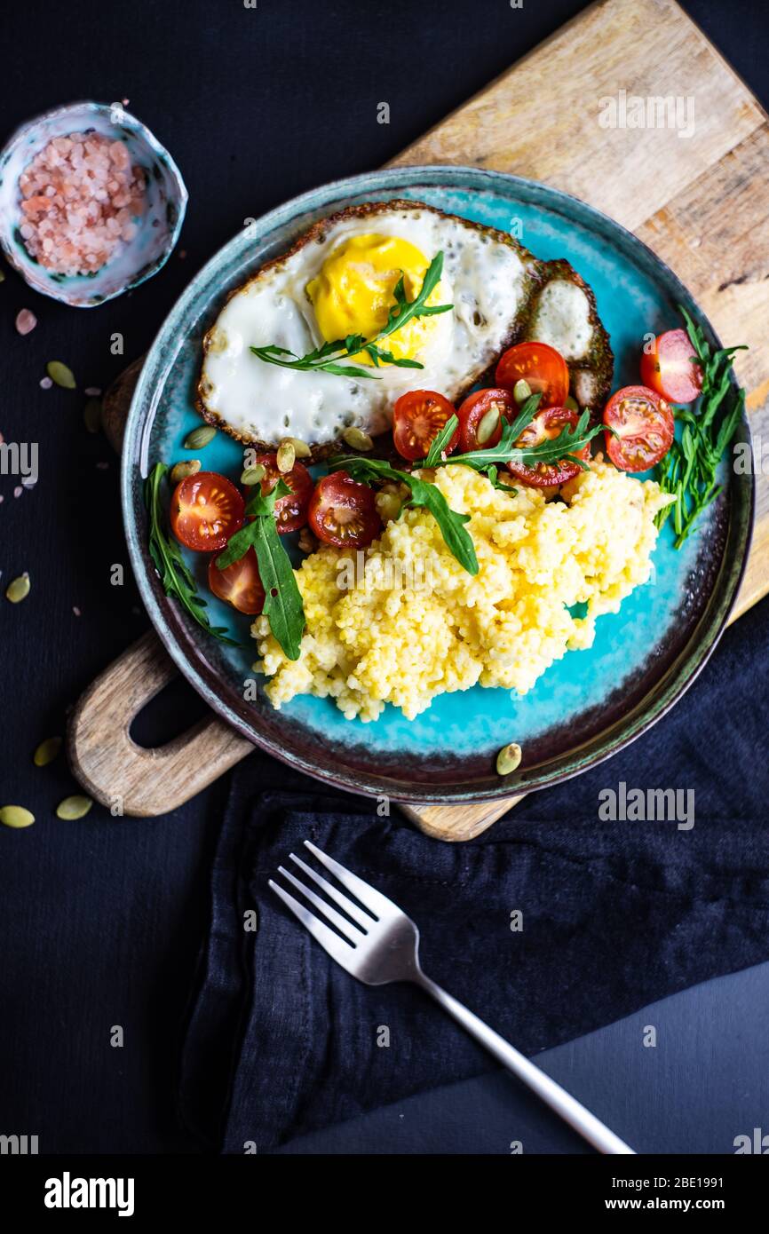 Healthy breakfast concept with millet, fried egg and cherry tomato with ...