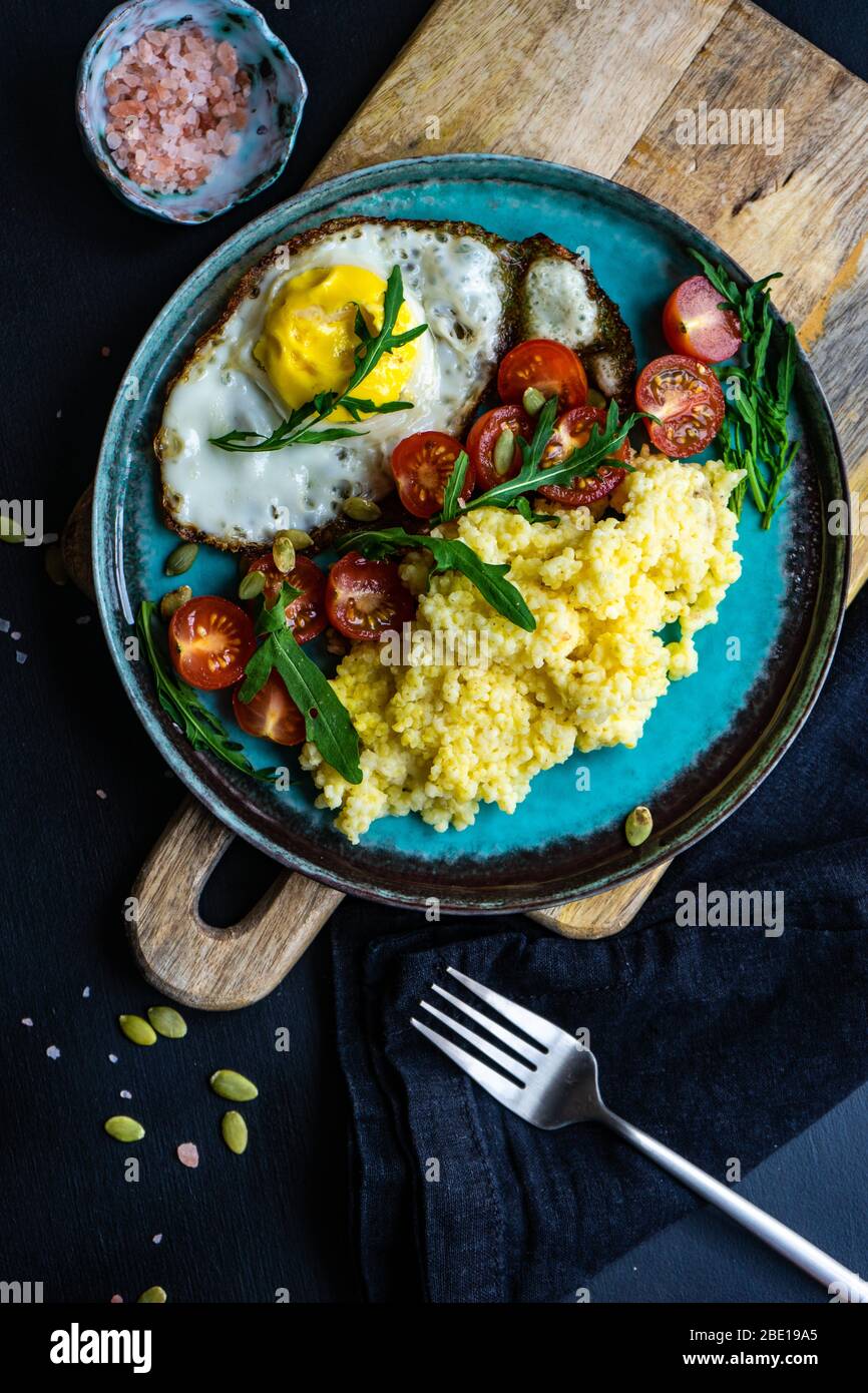 Healthy breakfast concept with millet, fried egg and cherry tomato with ...