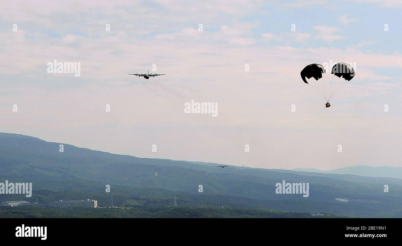 A cross parachute carries a cargo load dropped out of a C-130 Hercules ...