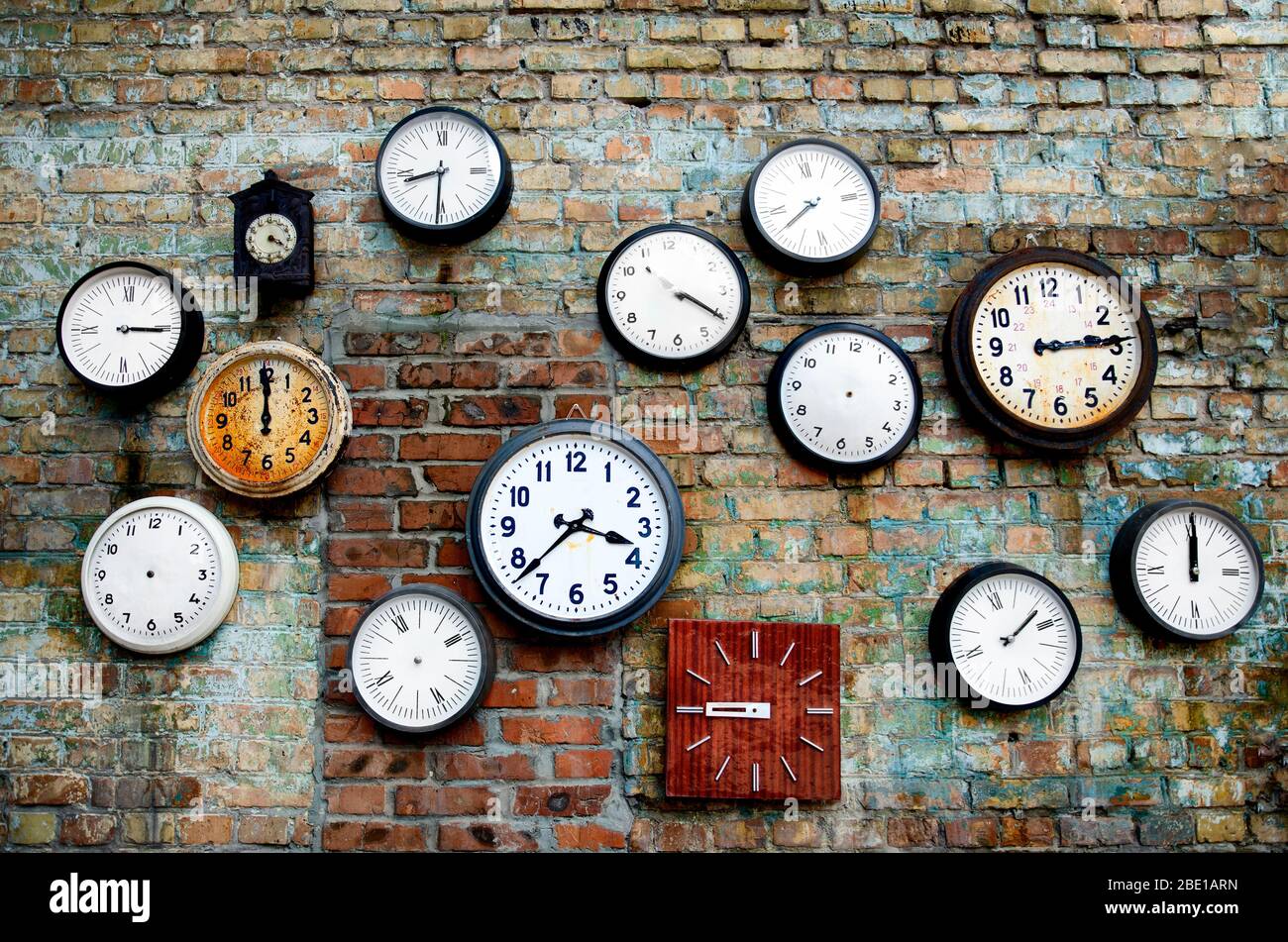 A lot of vintage clocks of different sizes hanging on a grunge brick ...