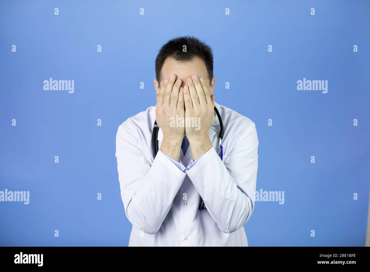 Middle-aged shocked doctor covering face with hands because of mistake ...