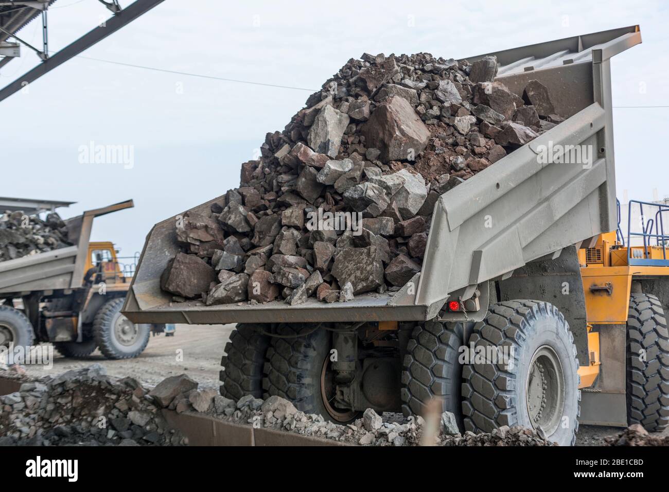 Mining industry: heavy dump trucks unload granite into huge rock ...