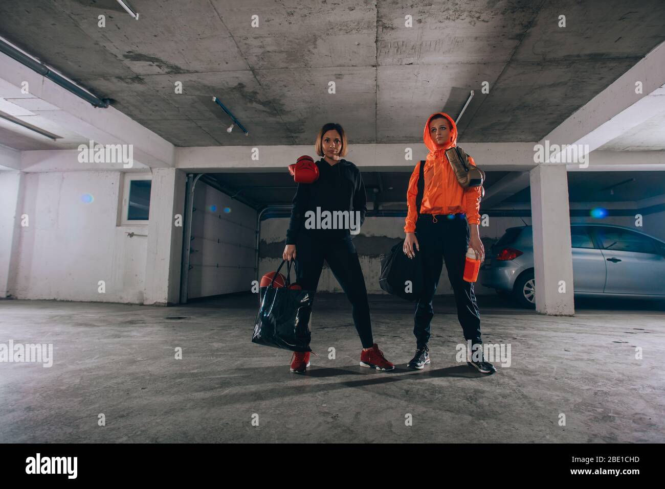 Two female boxer friends standing in a garage with boxing equipment ...