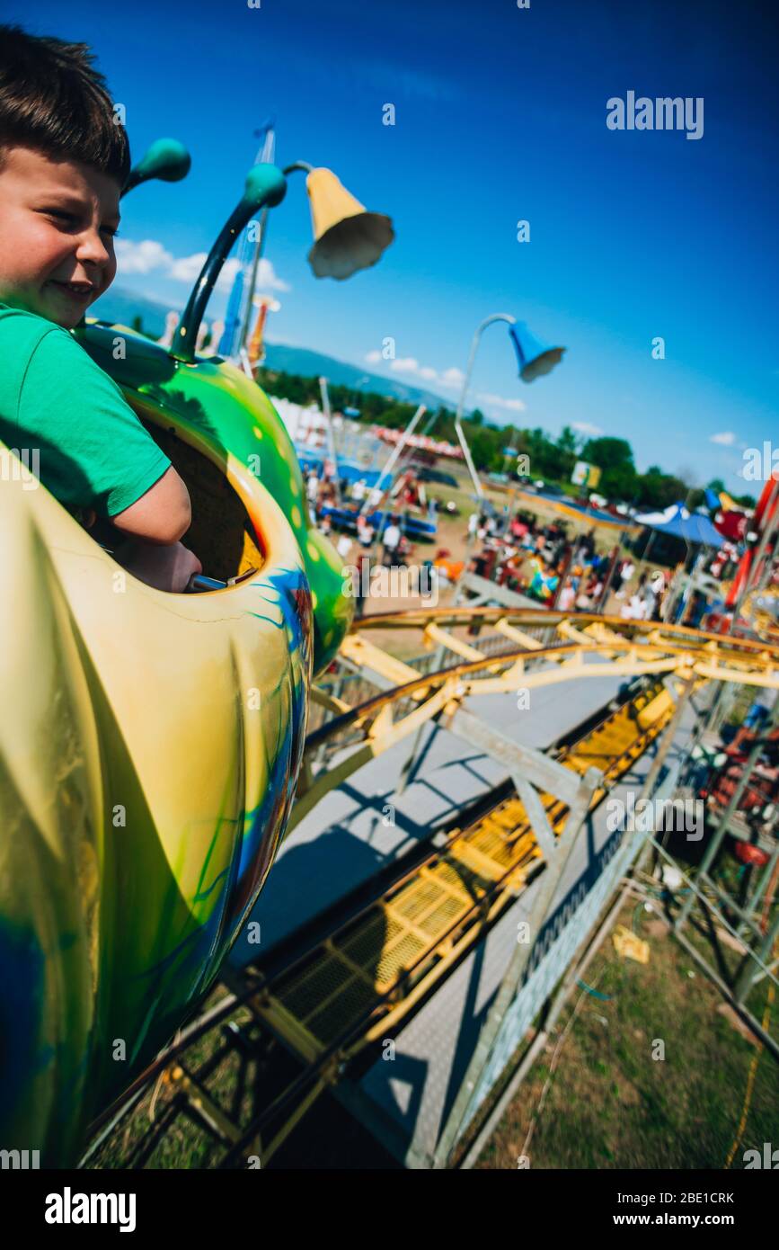 Teenager and his kid brother riding a roller coaster at a theme park ...