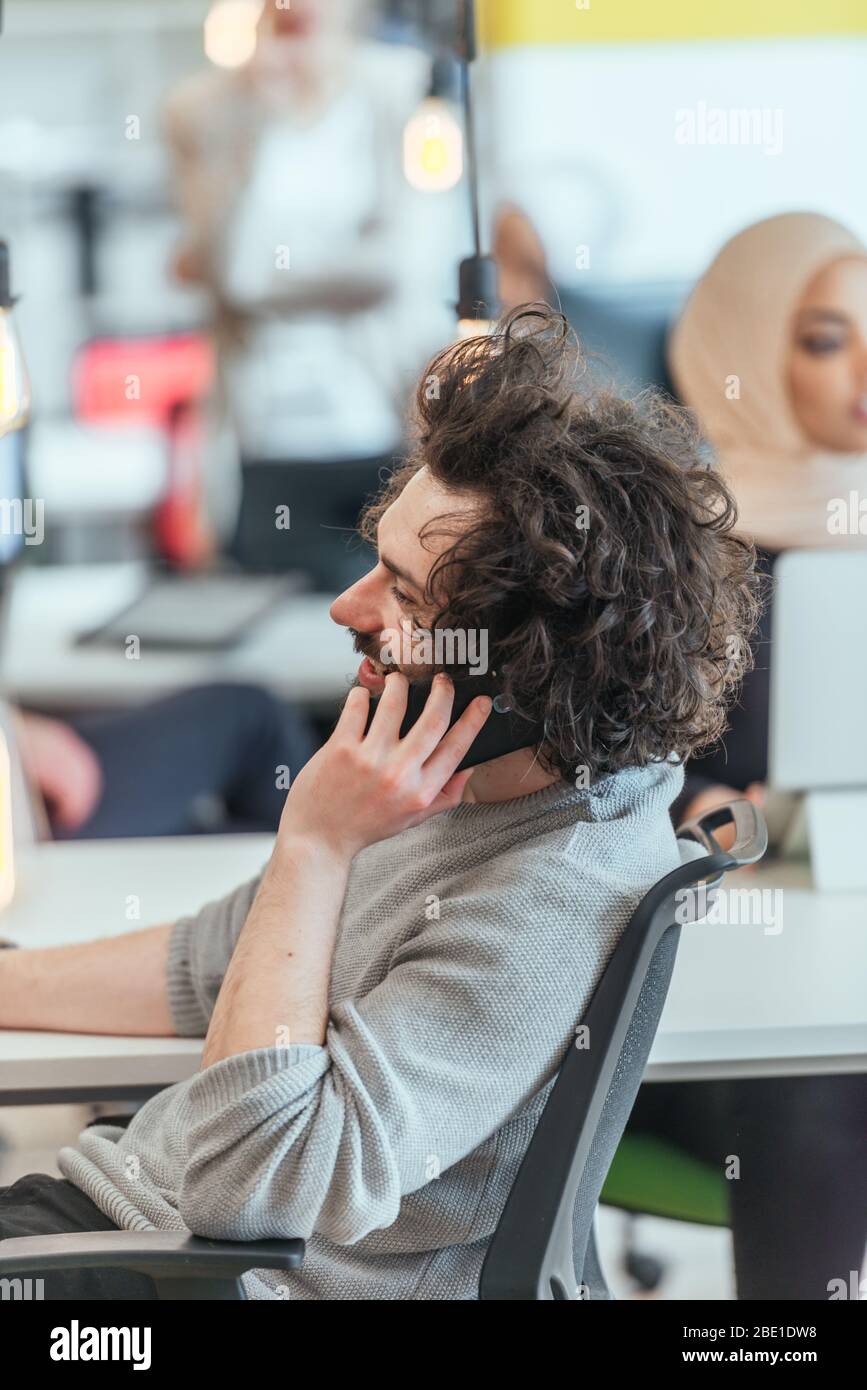 Bearded employee guy with afro haircut talking on his phone while being ...