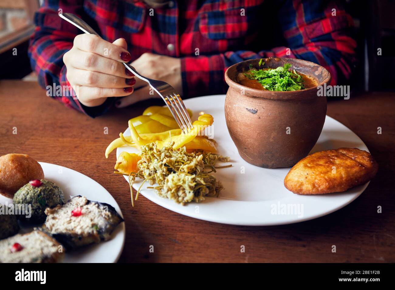 Woman eating beans at clay pot and vegetarian snakes pkhali Georgian ...