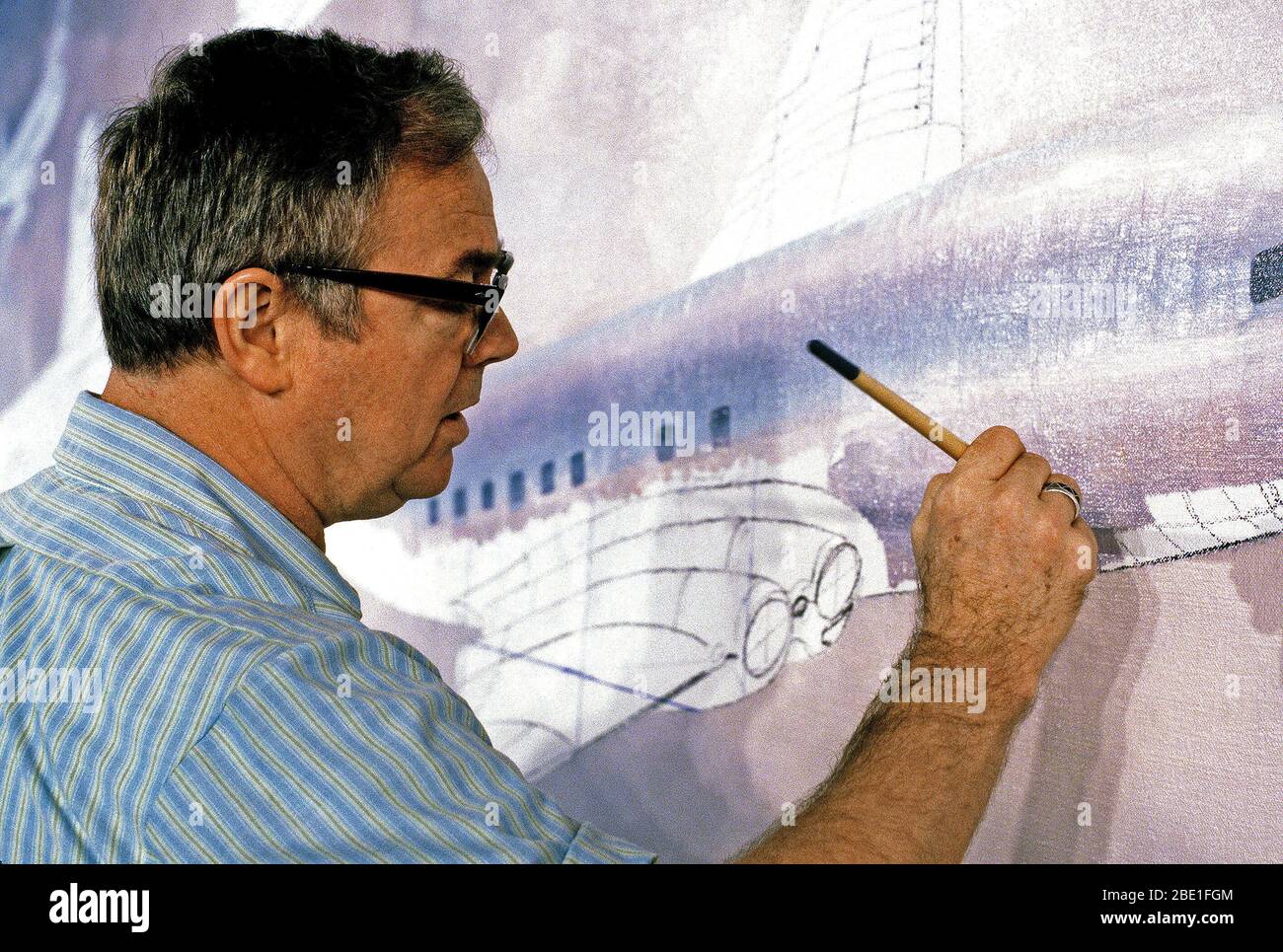 Close up of an aviation artist as he paints a mural picture of in ...