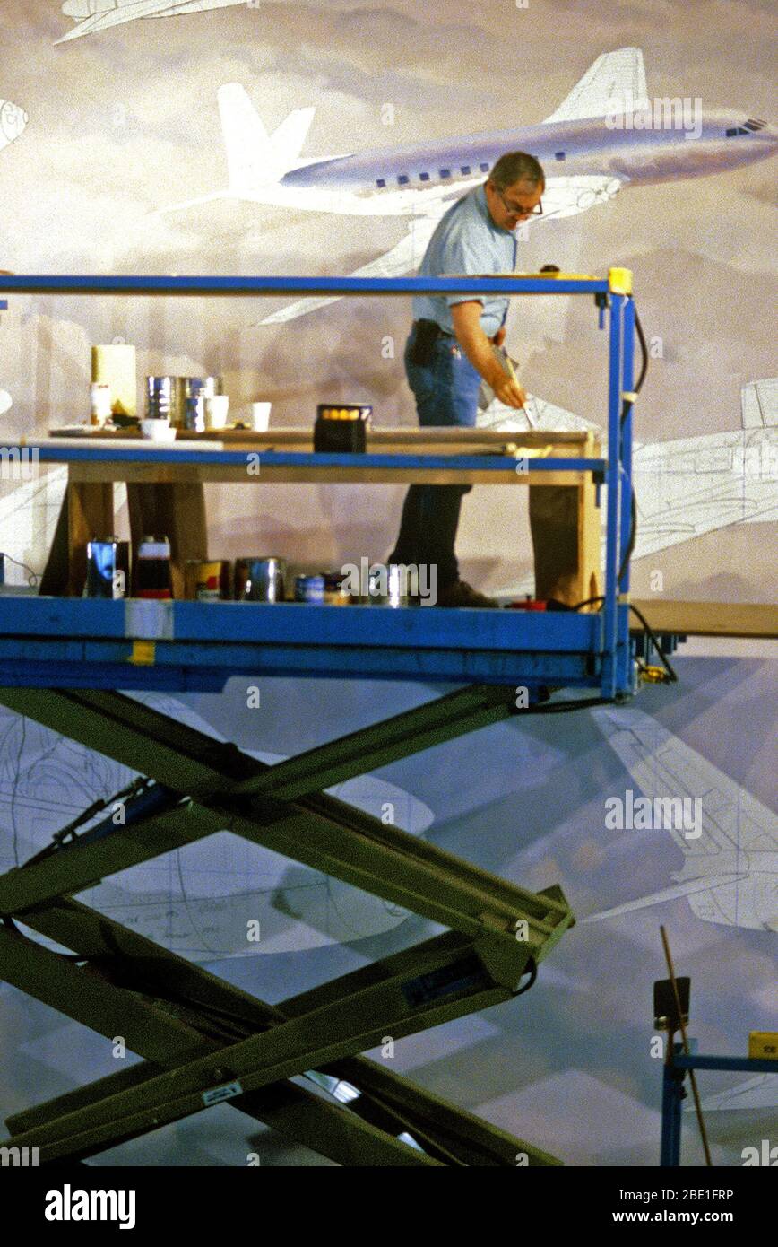 An aviation artist, paints a mural picture of aircraft, in flight, at ...