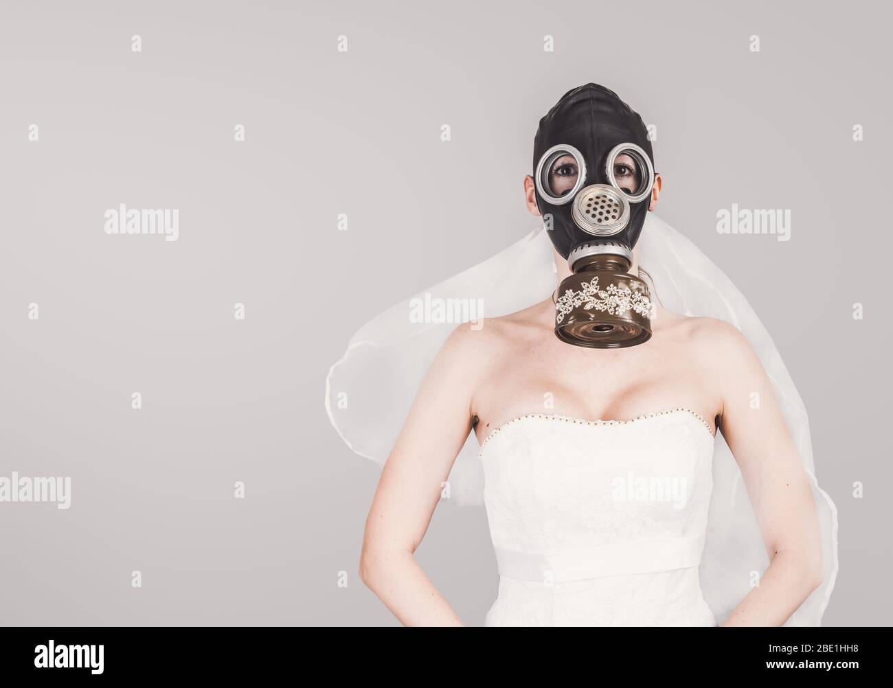Beautiful young bride in a wedding dress and protactive gas mask on her ...