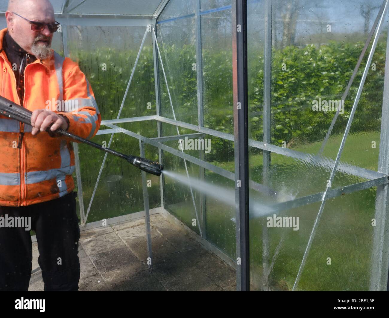Construction worker cleaning filth with high pressure cleaner from a ...