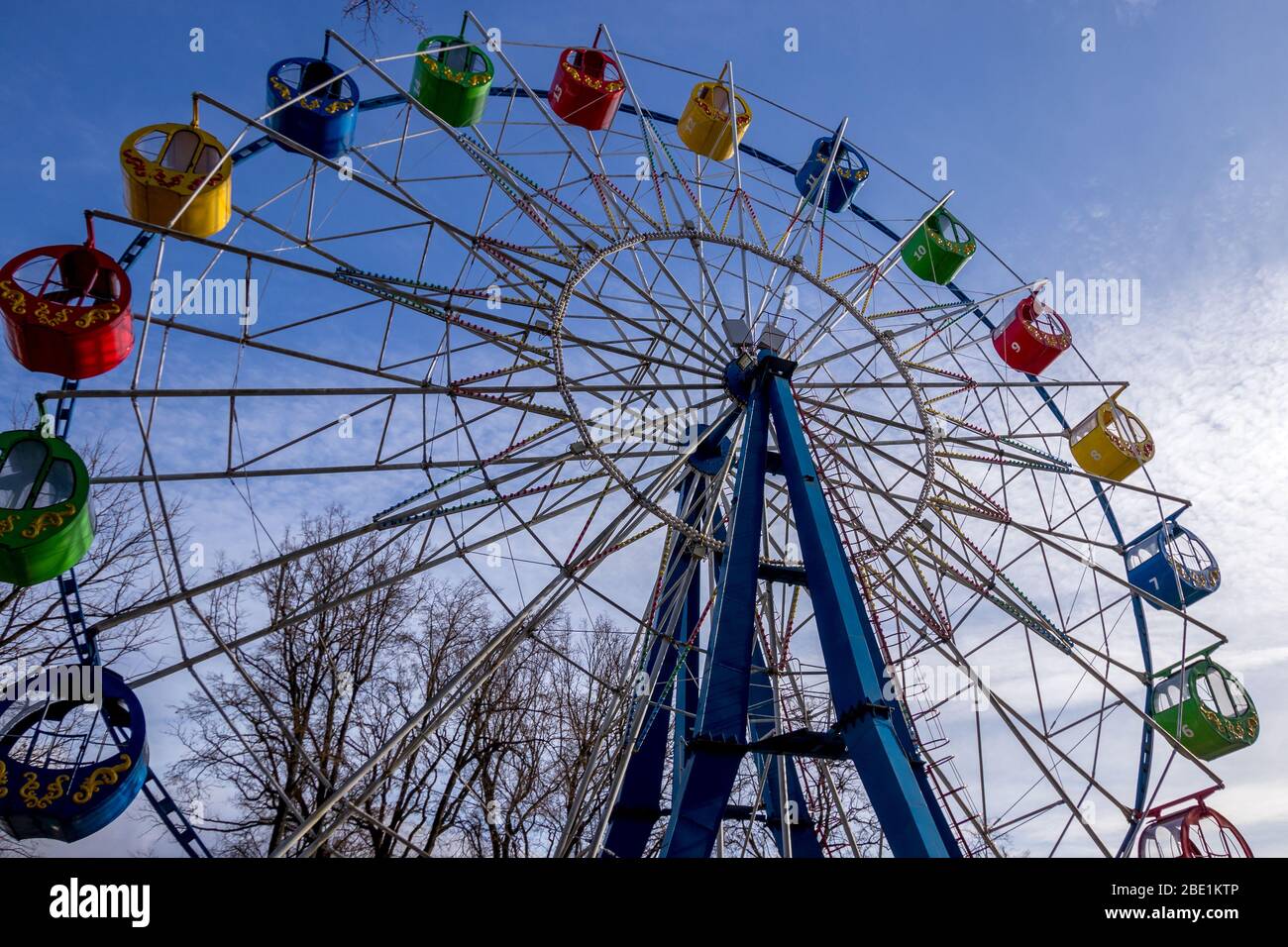 Ferris wheel with colorful cabs against the sky with clouds in the park ...