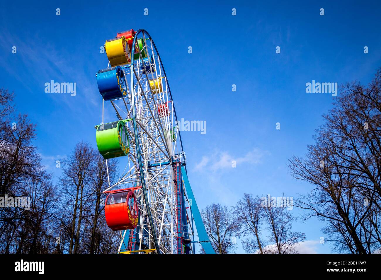 Ferris wheel with colorful cabs against the sky with clouds in the park ...