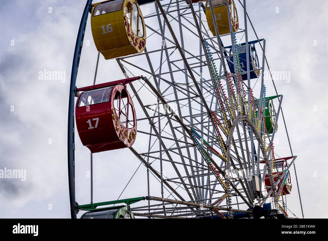 Ferris wheel with multi-colored cabs against the sky with clouds in the ...