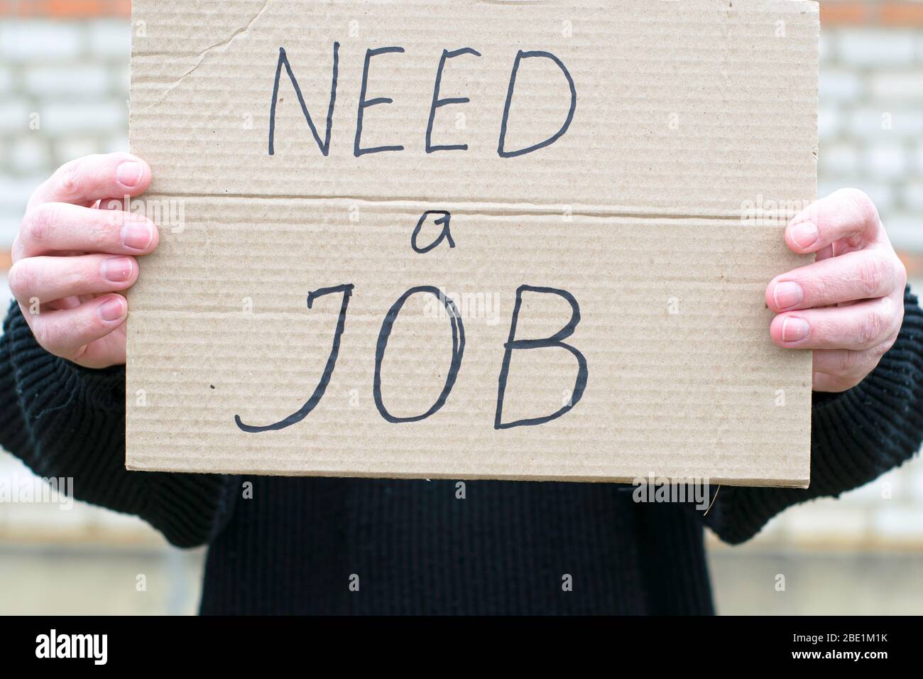 unemployed person holding a cardboard sign with the inscription need a ...