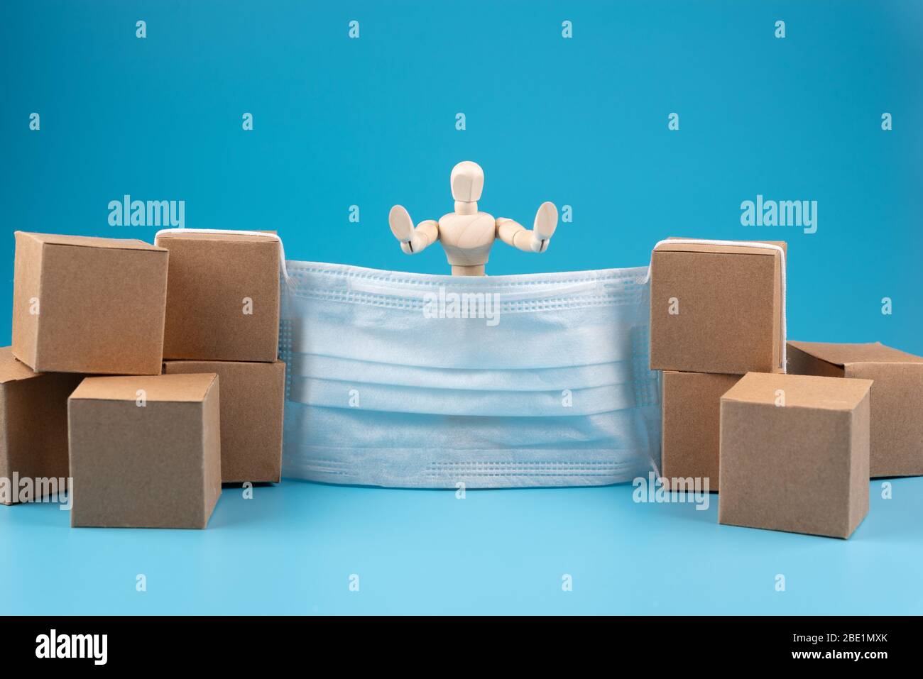 Wooden human with cardboard boxes and protective mask on blue ...