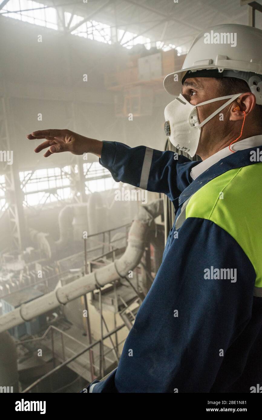 Mining engineer in white helmet respirator supervises work of granite ...