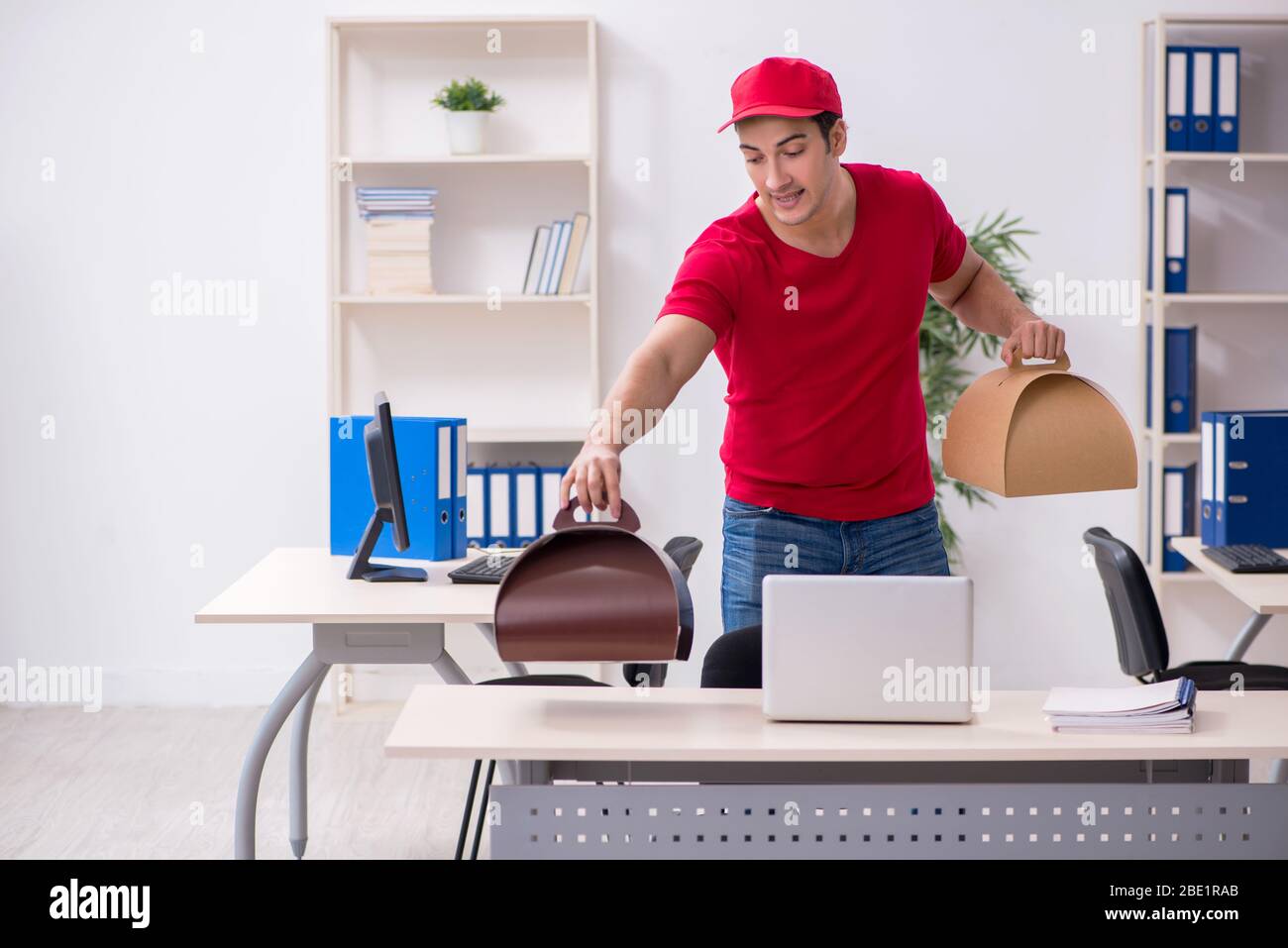Young courier delivering cake to the office Stock Photo - Alamy