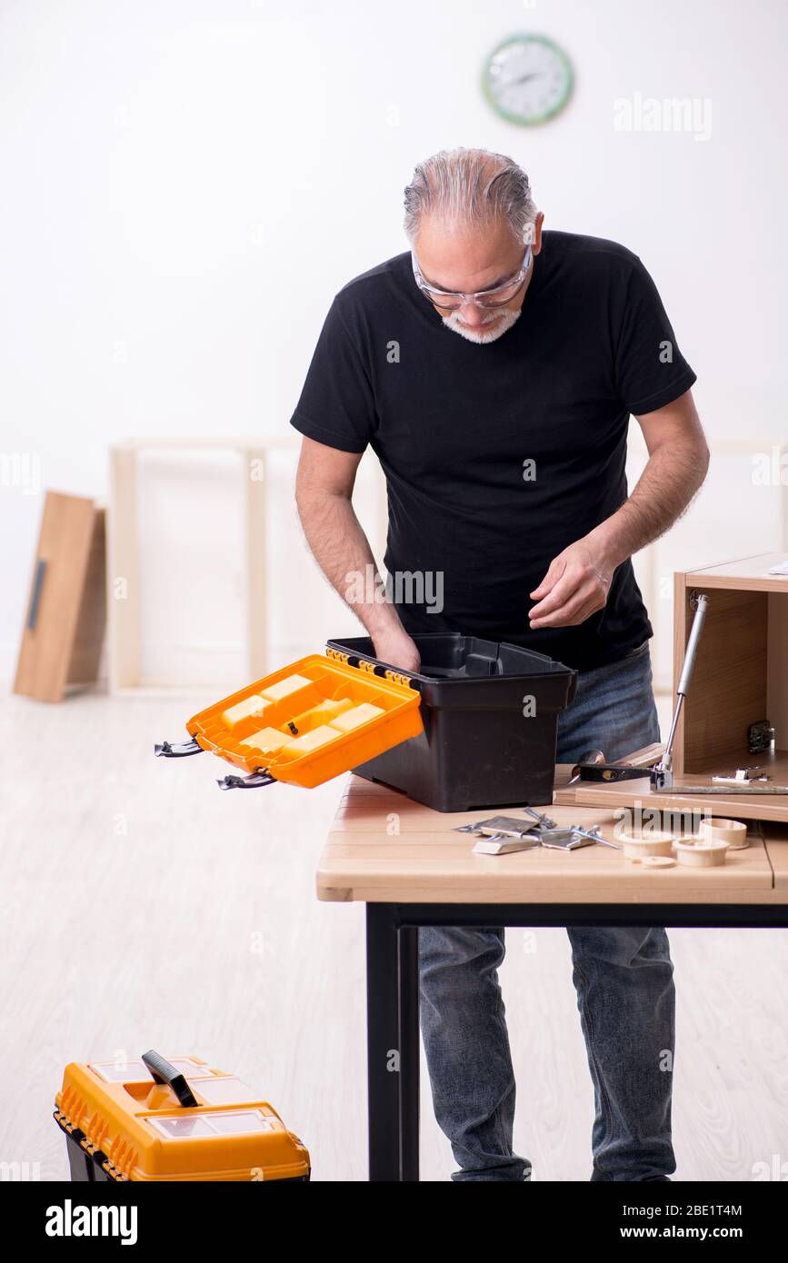 Old carpenter working indoors on furniture Stock Photo - Alamy