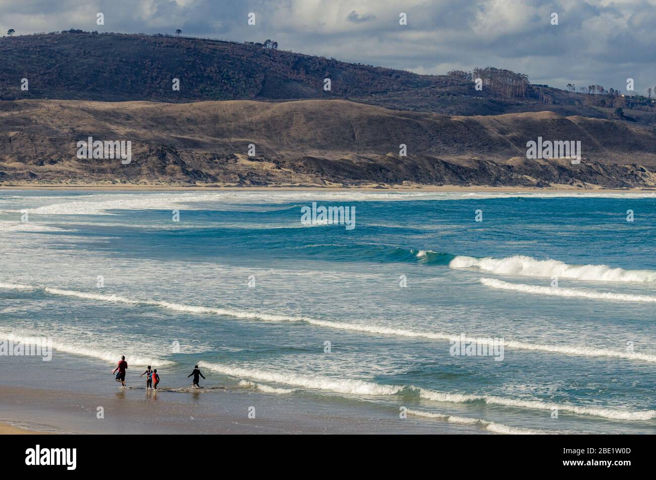 Long shot of African family walking and playing in the surf on buffalo ...