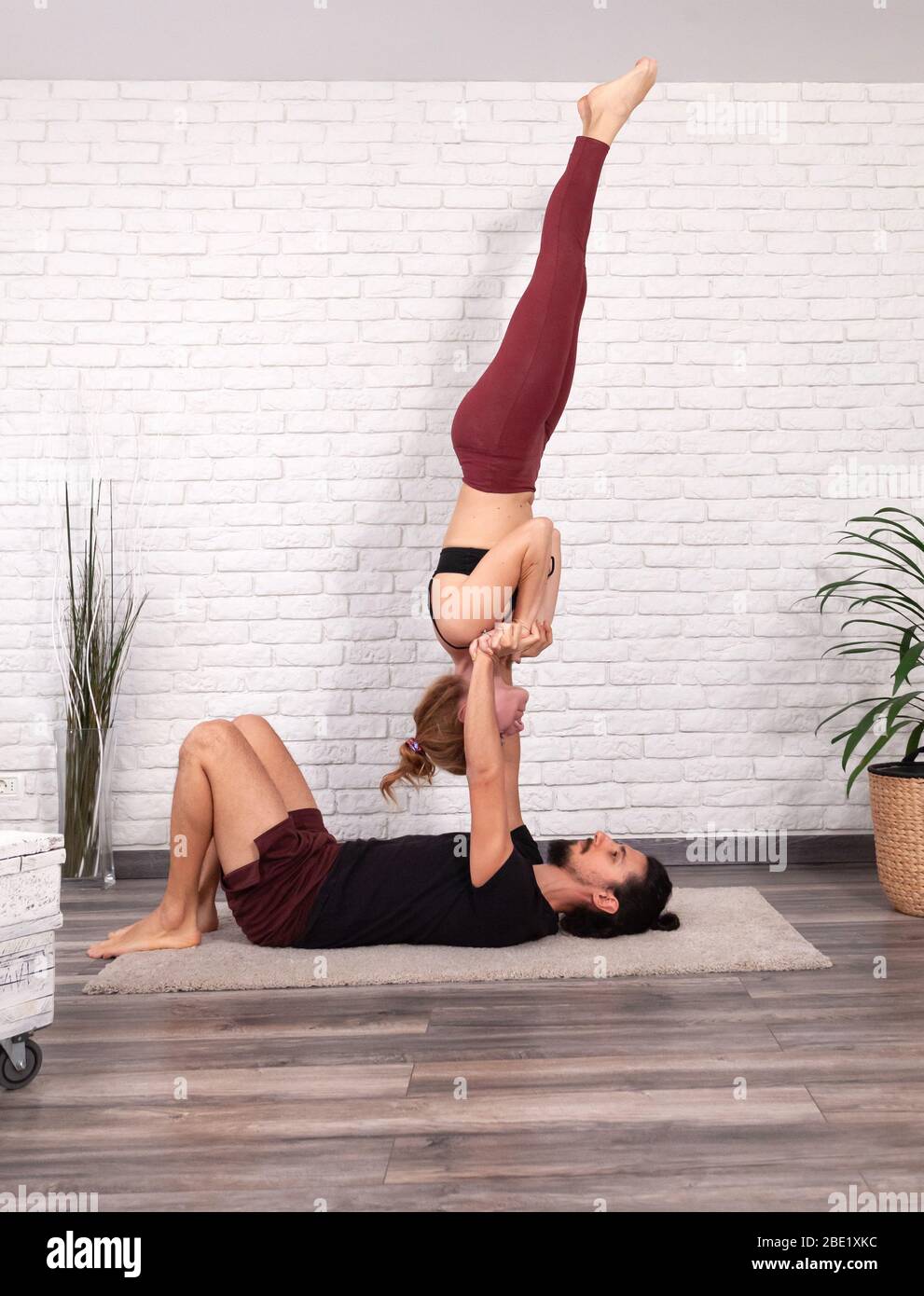 Young couple having fun at home with some acro yoga poses in different ...