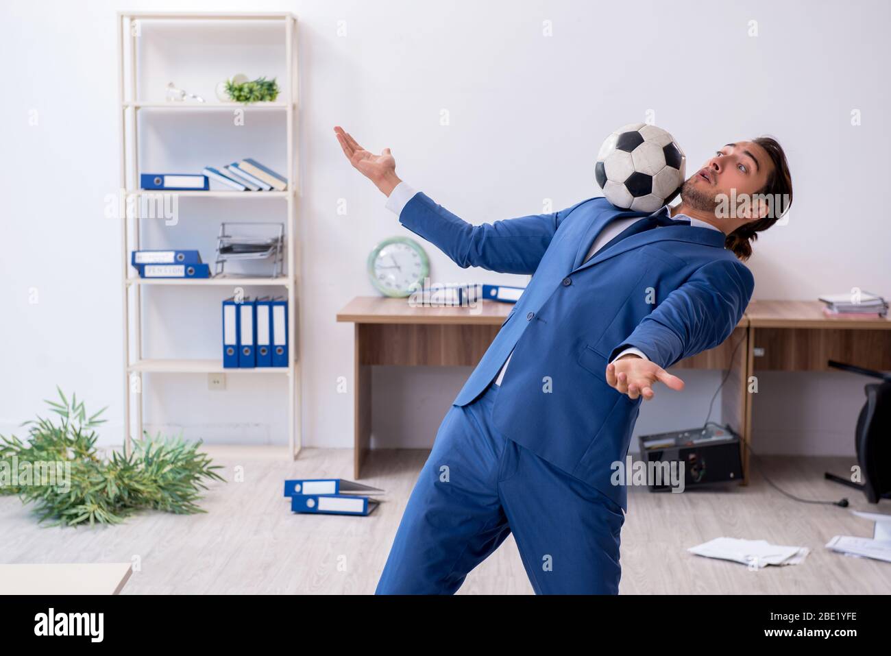 Young employee playing football in the office Stock Photo - Alamy