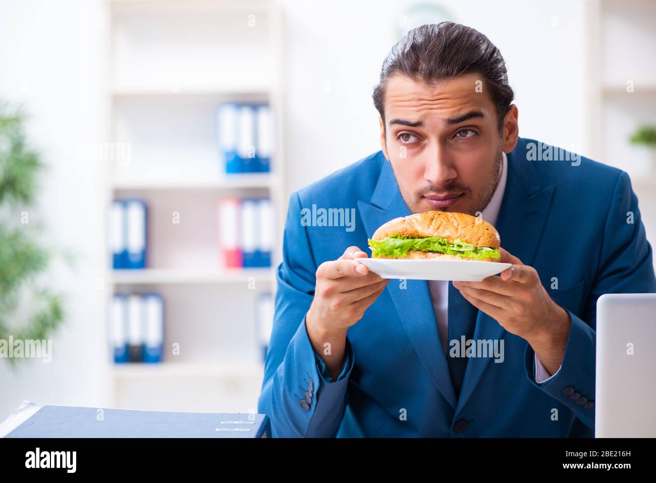 Young employee having breakfast at workplace Stock Photo - Alamy