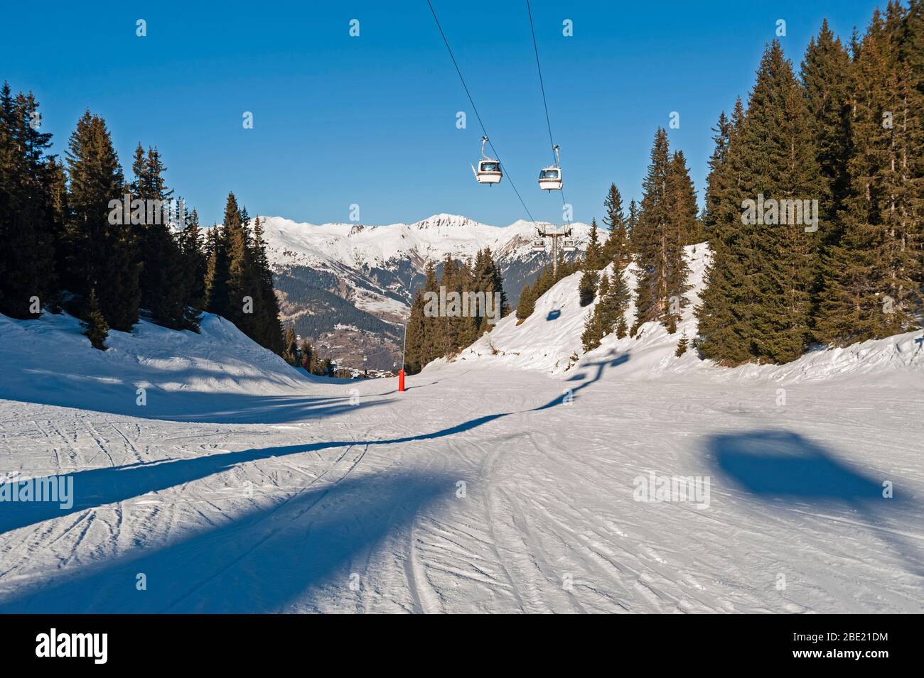 View of an alpine ski slope piste with cable car lift on mountain side ...
