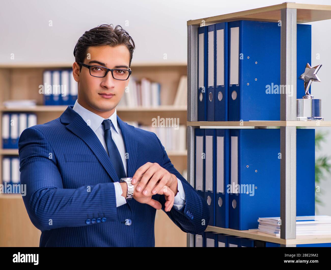 The young man standing next to the shelf with folders Stock Photo - Alamy