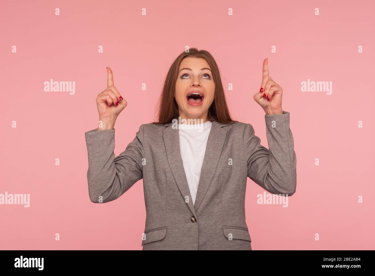 Wow, look above at advertisement! Portrait of surprised young woman in ...