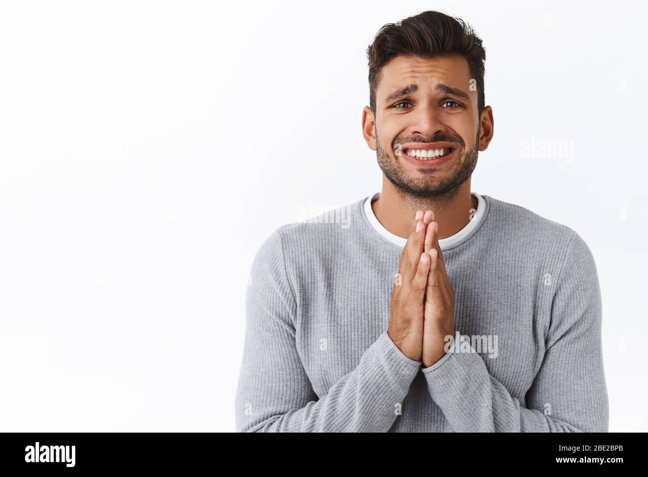 Close-up silly and cute guy really need your help, press hands together ...