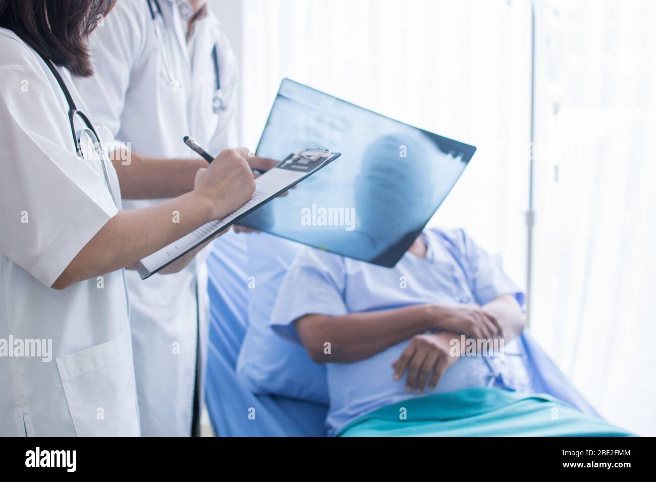 doctor writing on paper and looking at X-ray film Stock Photo - Alamy