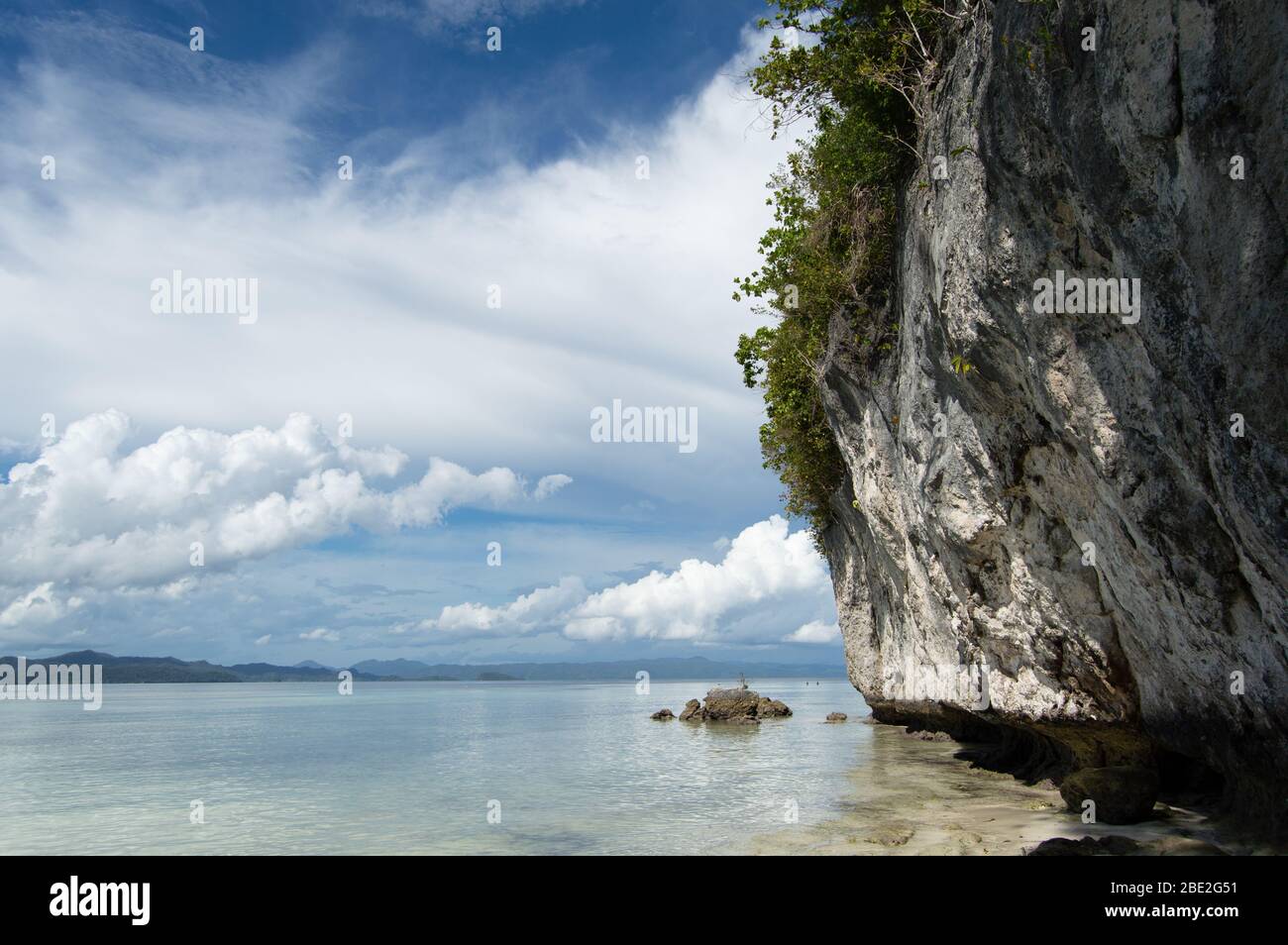 Tropical white limestone cliff over the calm sea in Kri island, Raja ...