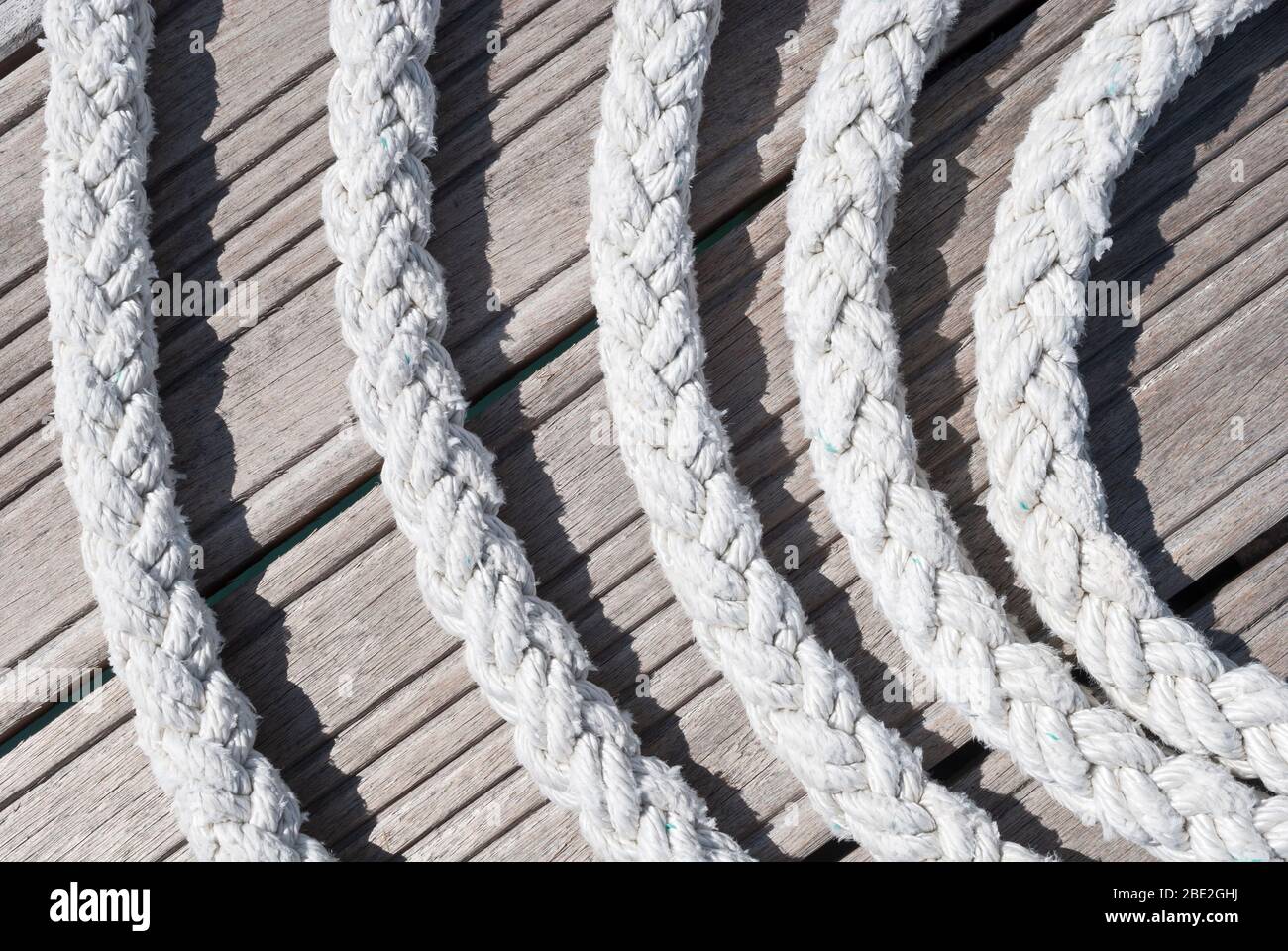 Thick white nautical rope forming a loose abstract spiral outdoors on a ...