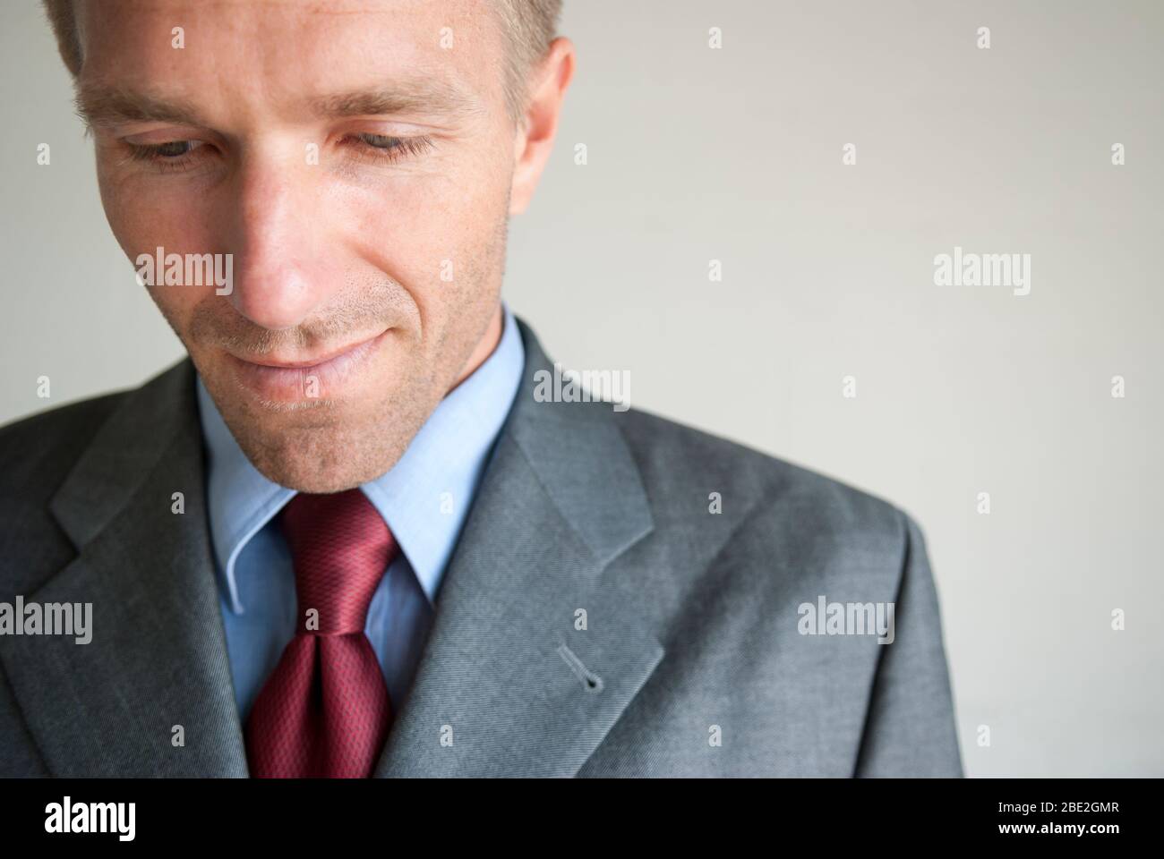 Portrait of cheerful businessman looking down with a smile in a head ...